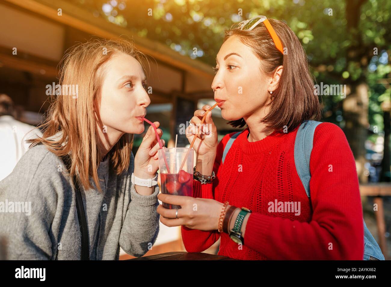 Friends smiling and drinking cocktail using straw Stock Photo - Alamy
