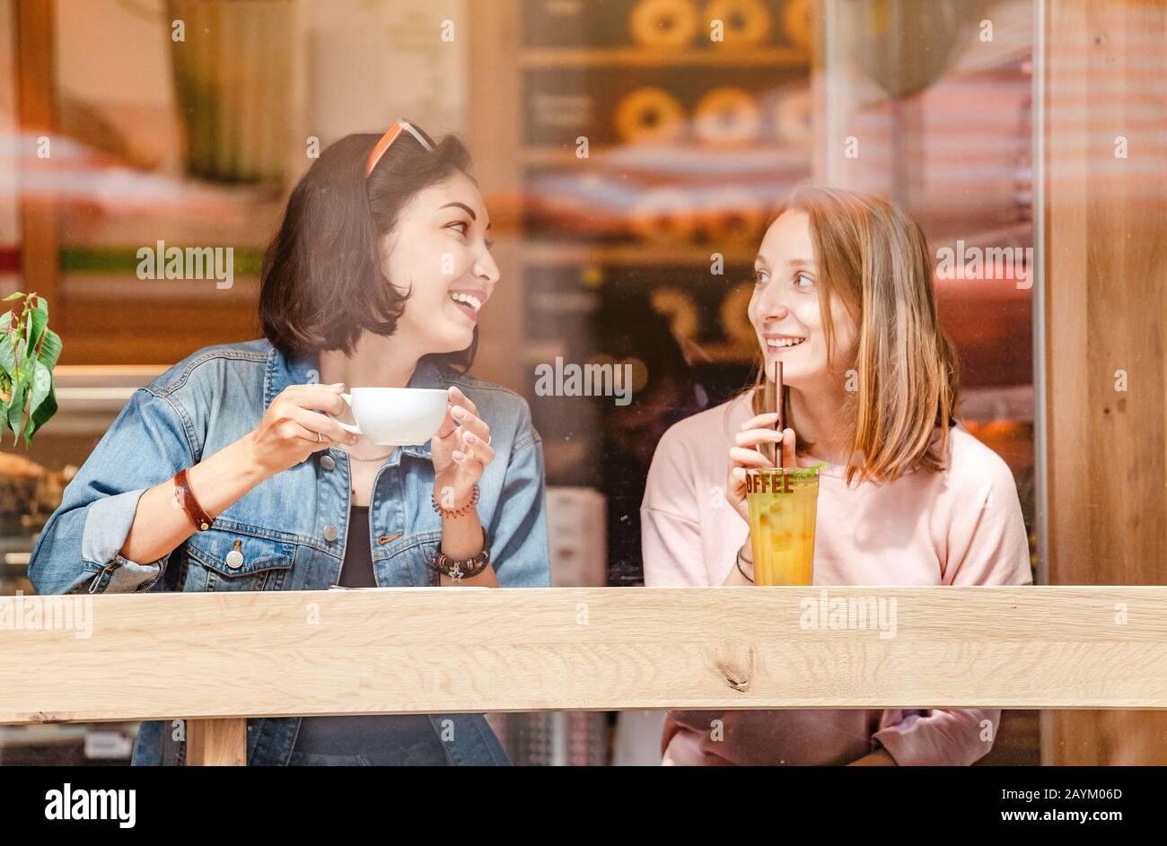 Two happy girls having lunch in a cafe, drinking coffe and talking ...