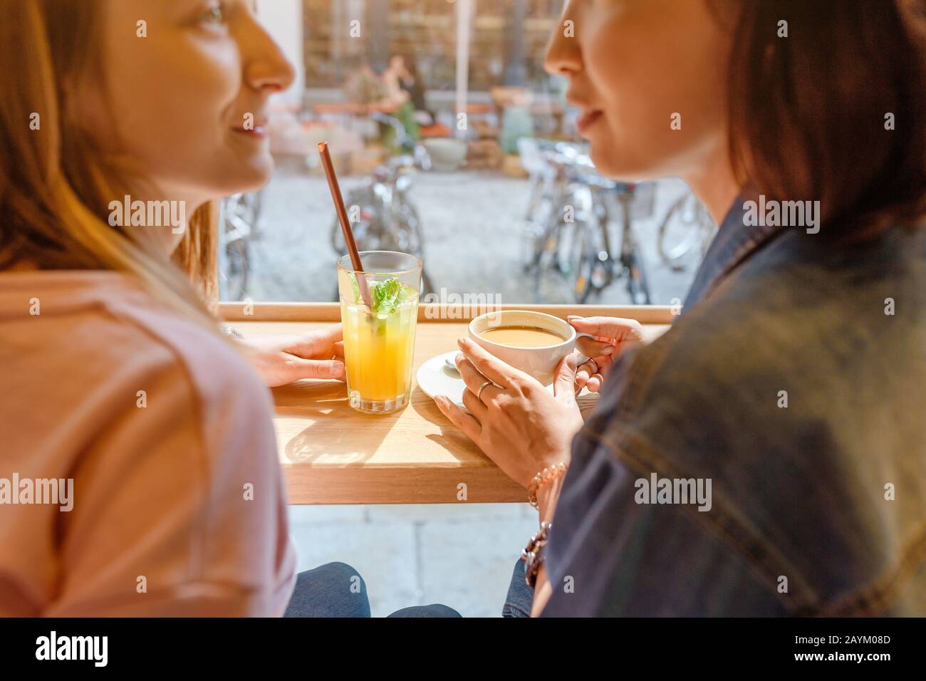 Two happy girls having lunch in a cafe, drinking coffe and talking ...