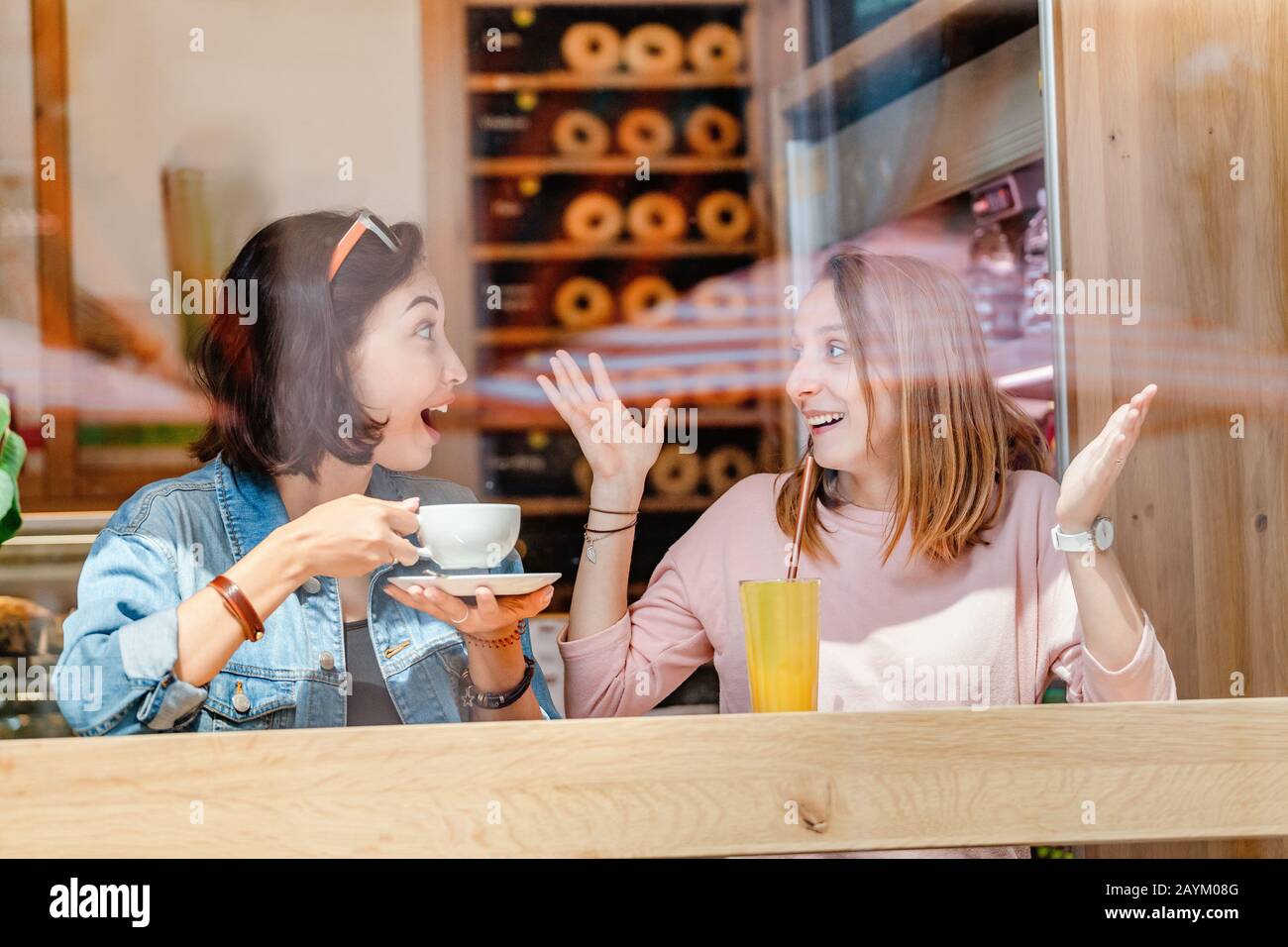 Two happy girls having lunch in a cafe, drinking coffe and talking ...
