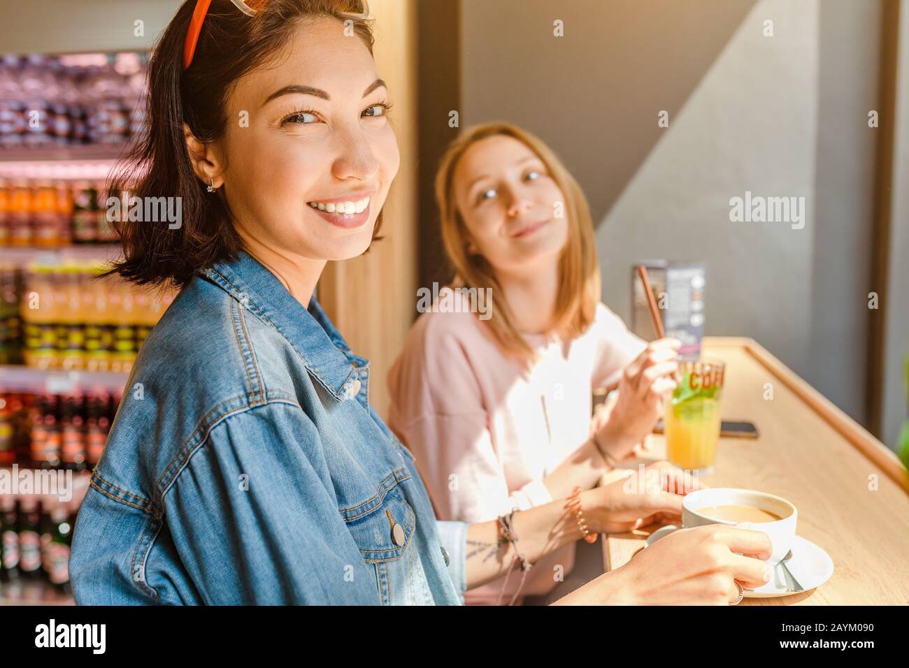 Two happy girls having lunch in a cafe, drinking coffe and talking ...