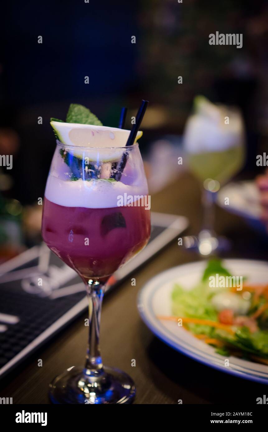 Cocktail based on bar counter with ice cubes and slice of lime ...