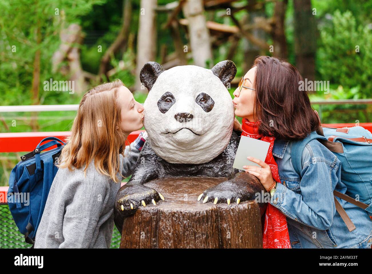 18 MAY 2018, BERLIN, GERMANY: Two young happy girls kissing a wooden ...