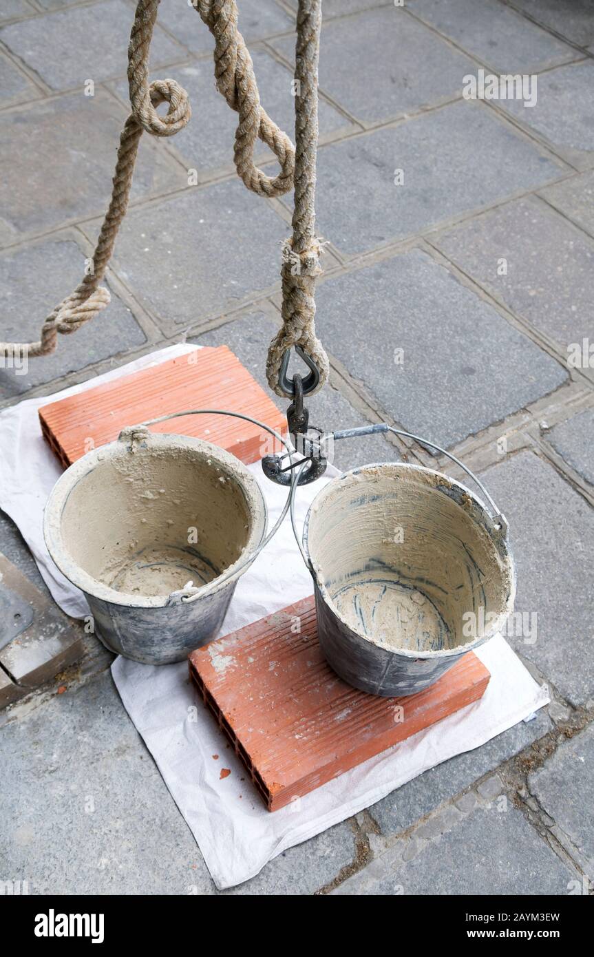 Two empty cement buckets hanging ready to be filled and pulled up on a ...