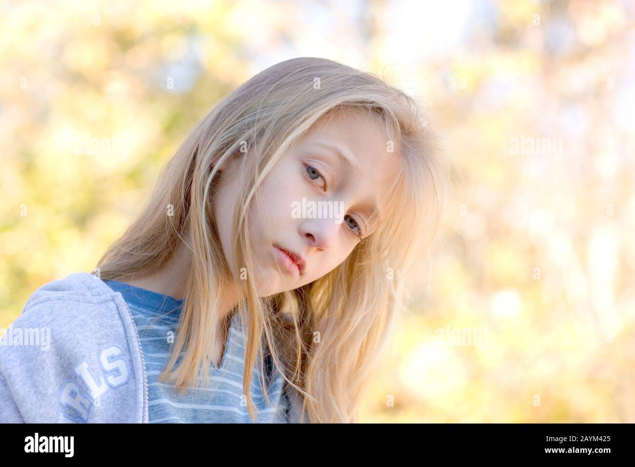 A confident, introspective pretty young girl with blond hair and blue ...