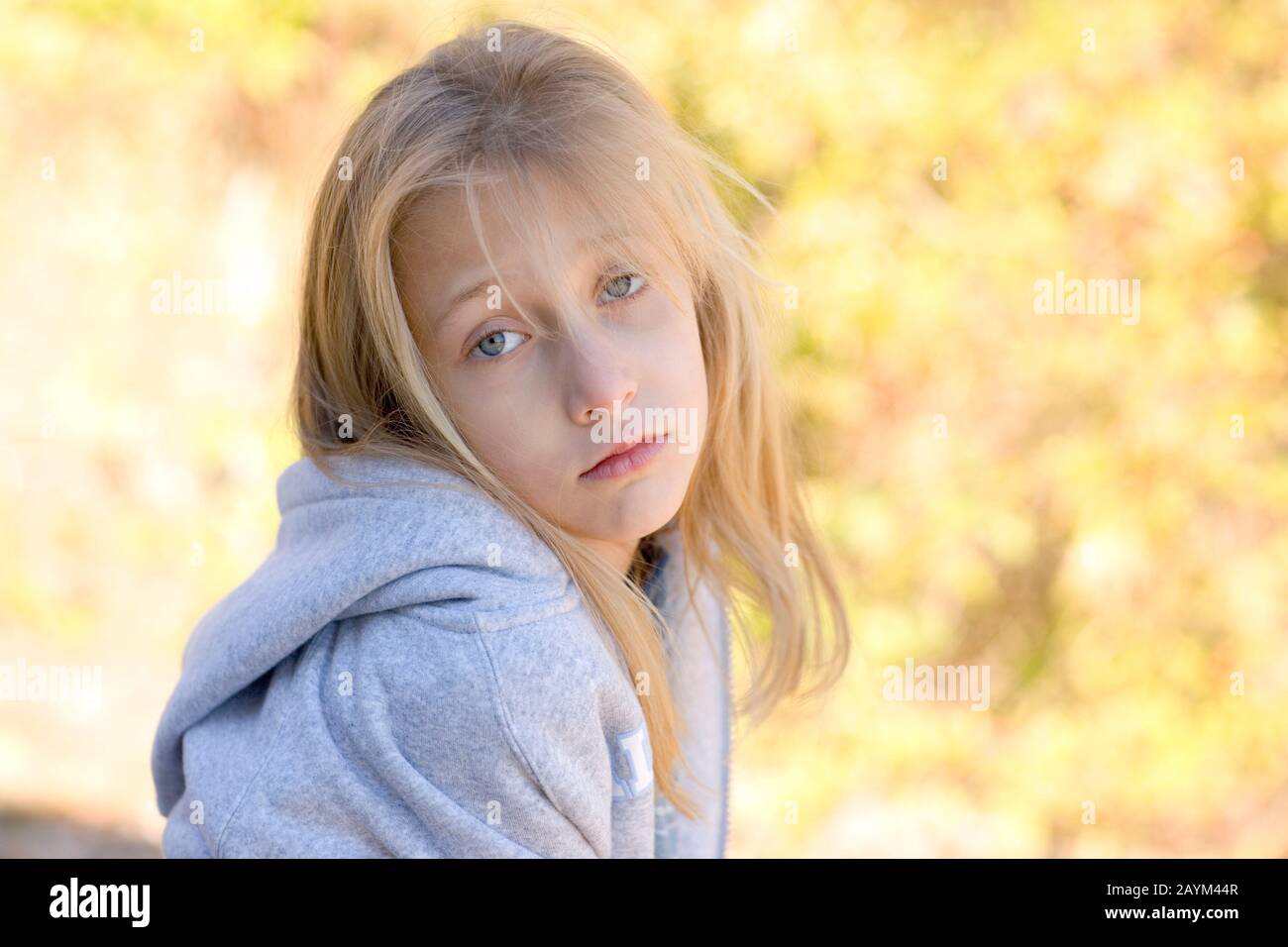 An introspective pretty young blond haired, blue eyed girl with a sad ...
