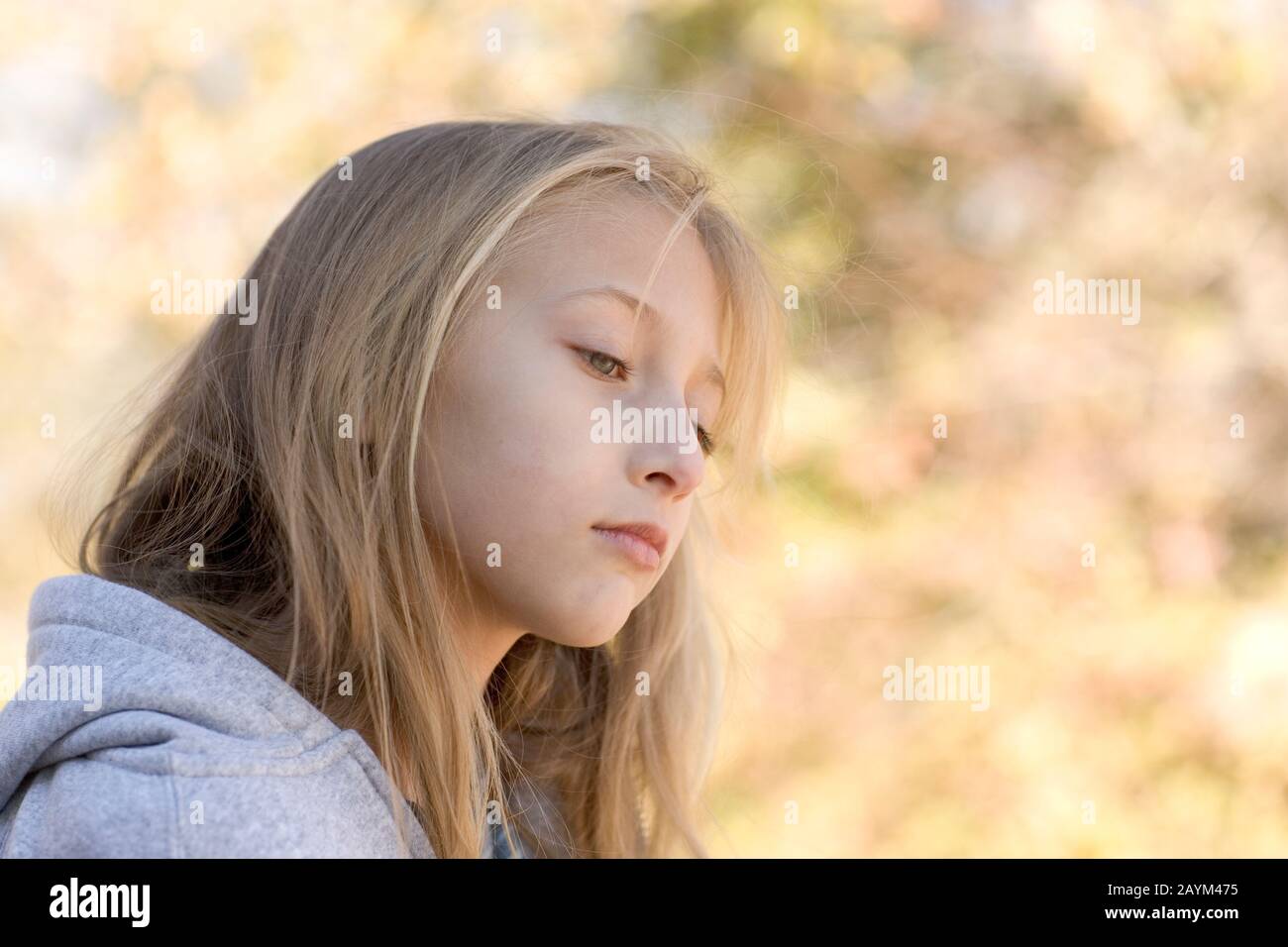 An introspective pretty young girl with blue eyes and tussled blond ...