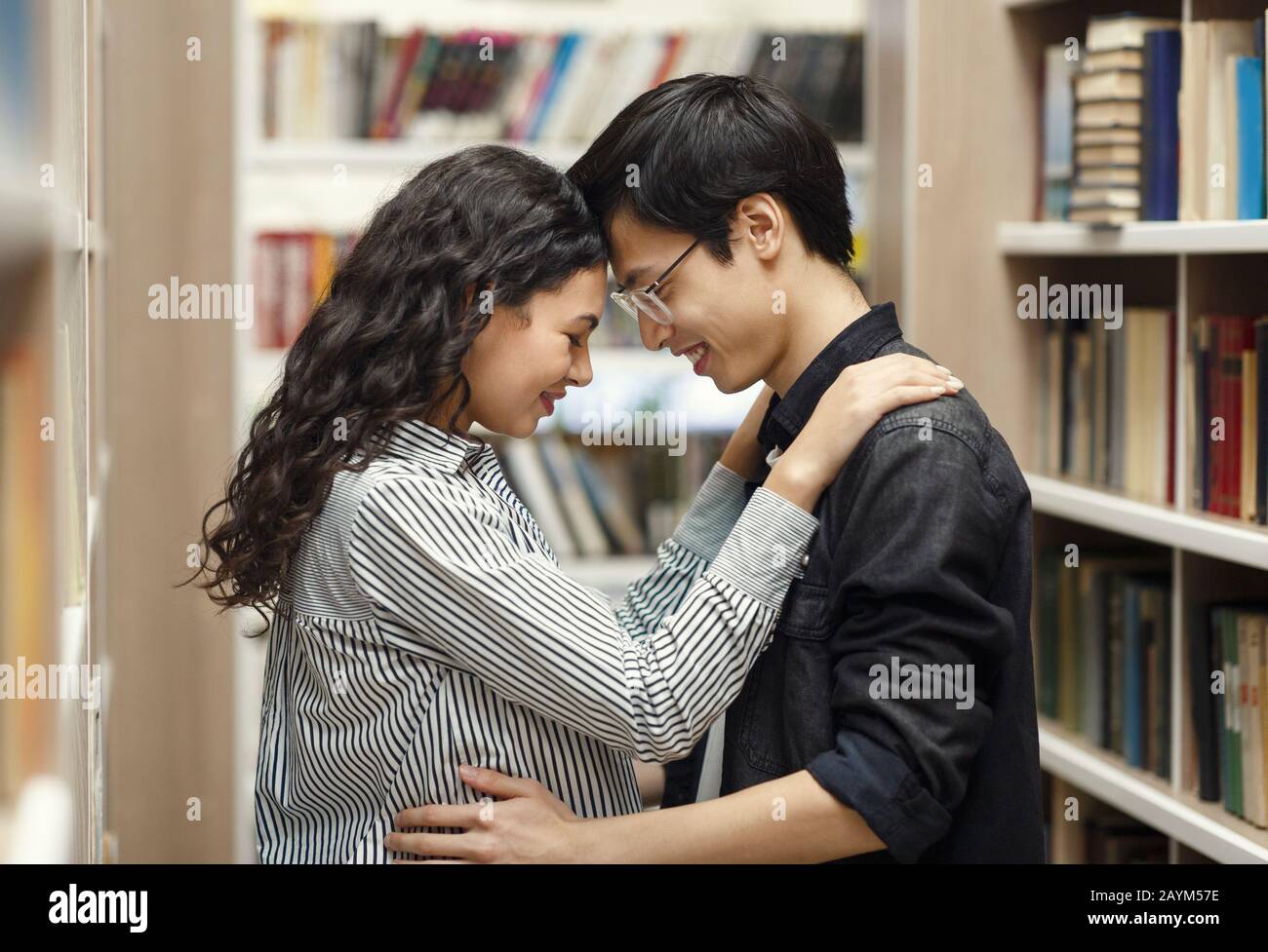 Two multicultural students hugging at modern library Stock Photo - Alamy