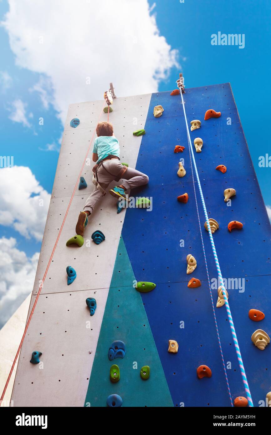 Little child boy on rock climb high on the wall in the sport park ...