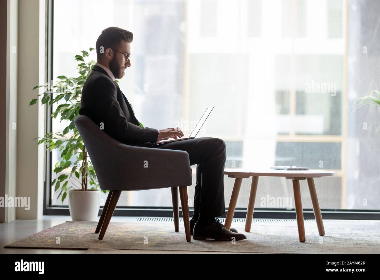 Arab businessman sitting in office lobby working on laptop Stock Photo ...