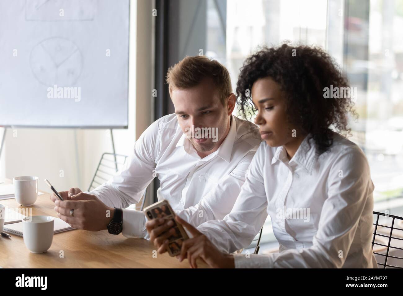 Multi-ethnic coworkers busy with smartphone new e-business application ...