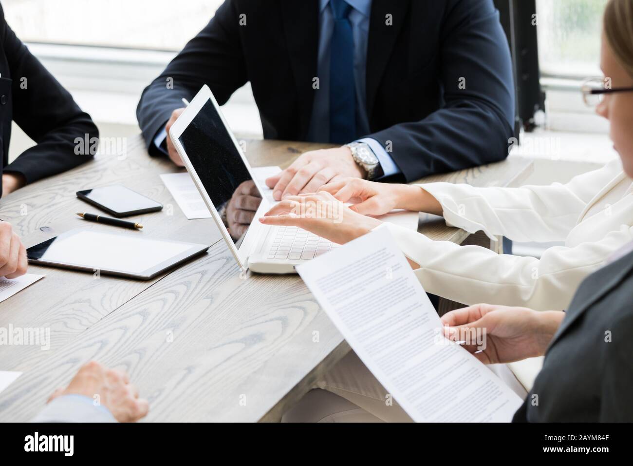 Business people sitting around the desk in a meeting and working with ...