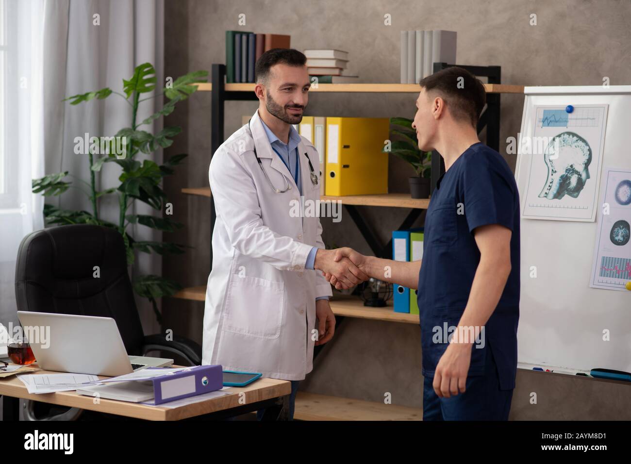 Two young doctors shaking hands in the staffroom Stock Photo - Alamy