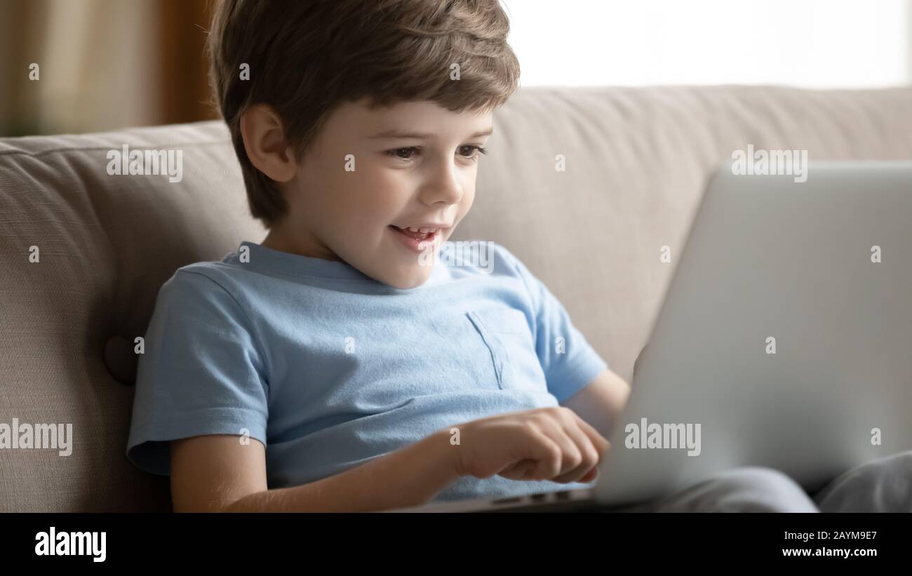 Small kid boy resting on couch, using educational app on laptop Stock ...