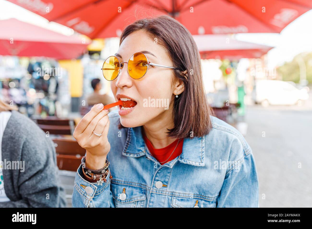 Woman eating Currywurst fast food German sausage in outdoor street food ...