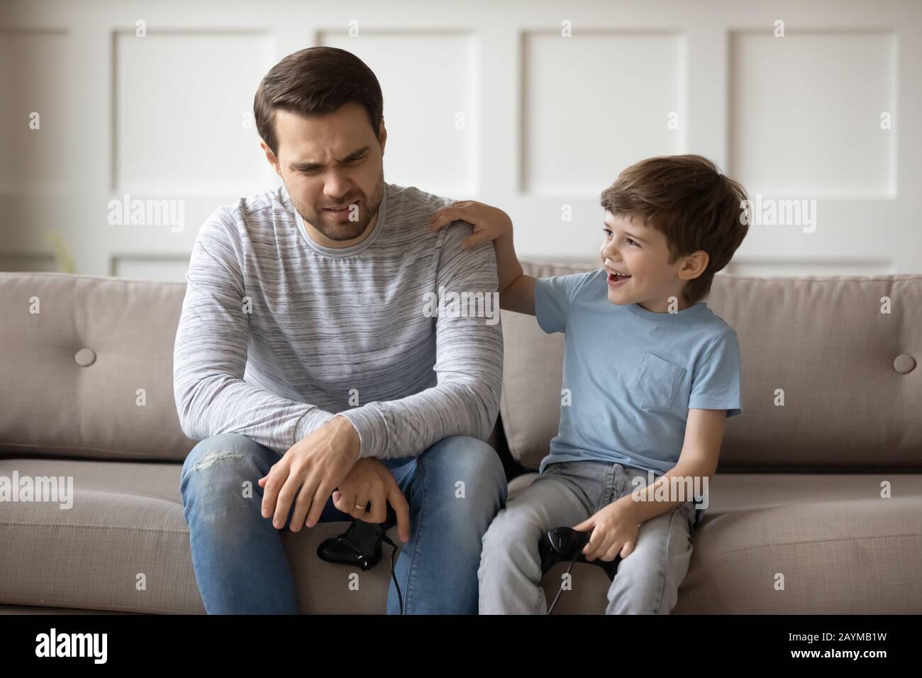 Happy small child supporting upset father after losing video game Stock ...