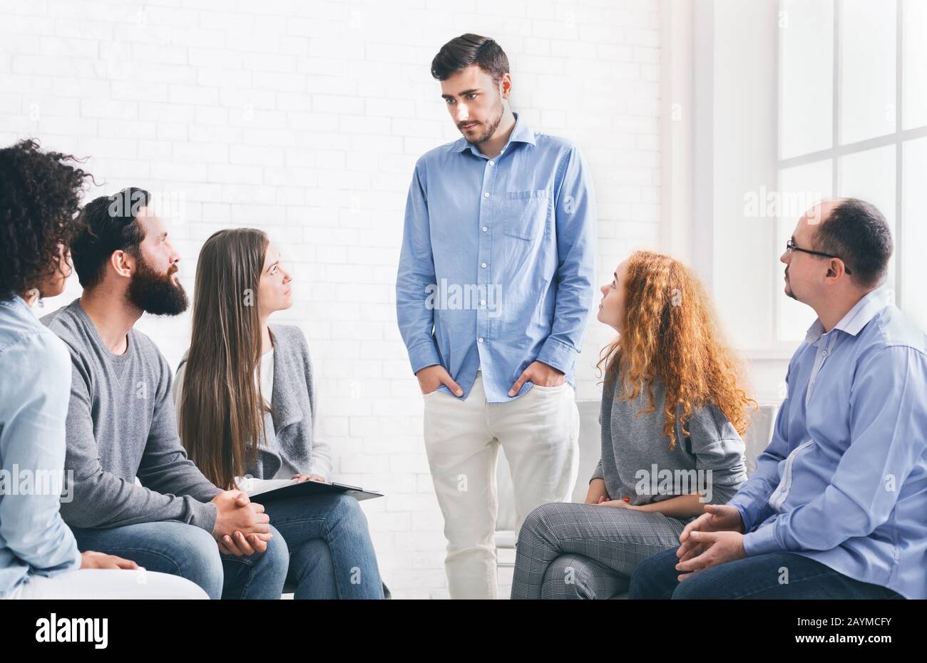 Young man talking about his problems during group therapy Stock Photo ...