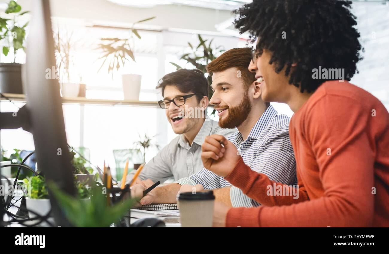 Three guys colleagues looking at laptop screen, celebrating success ...