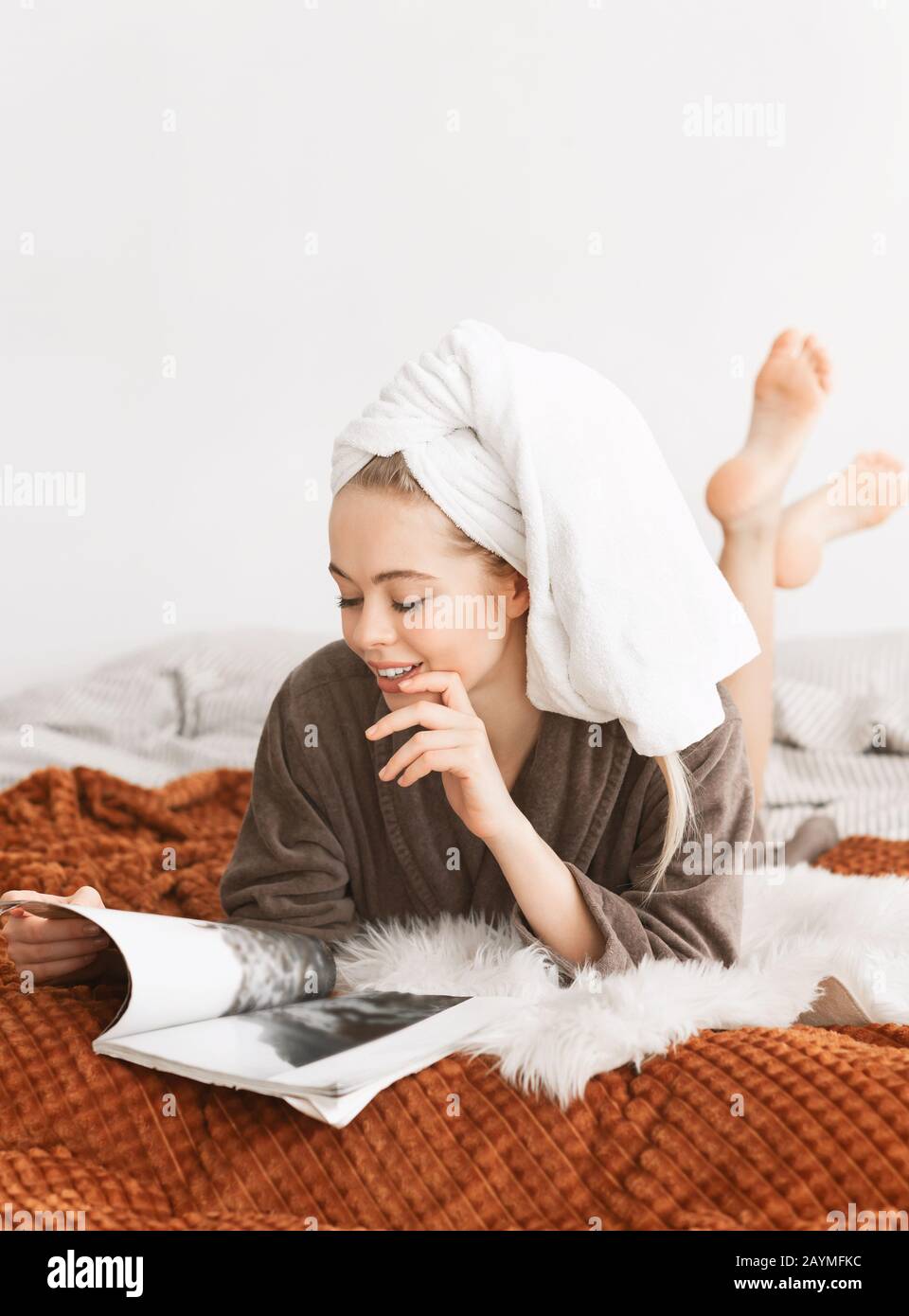 Relaxed blonde girl reading magazine, laying on bed at home Stock Photo ...