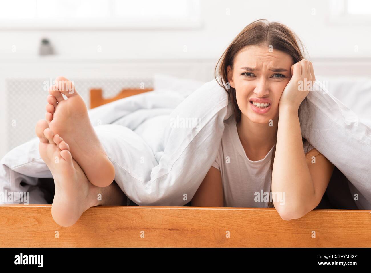 Disgusted Girl Lying Near Male Smelly Legs Grimacing In Bedroom Stock ...