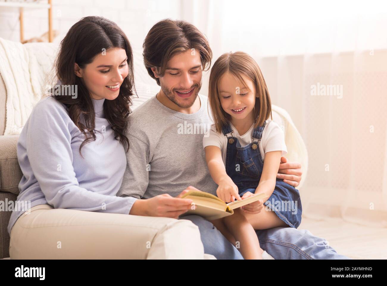 Parents teaching their little daughter how to read at home Stock Photo ...