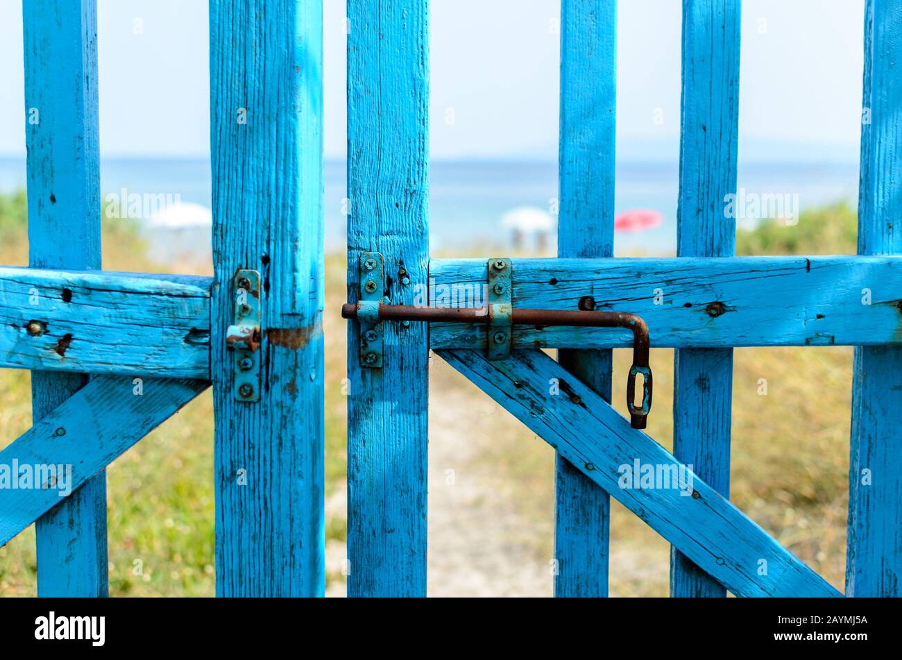 Unlocked blue wooden gate leading towards the sea, freedom concept ...
