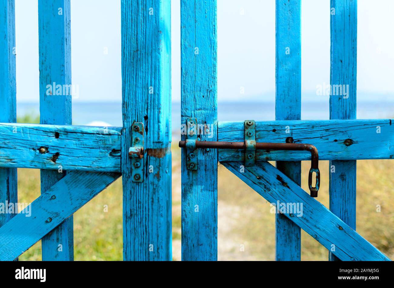 Unlocked blue wooden gate leading towards the sea, freedom concept ...