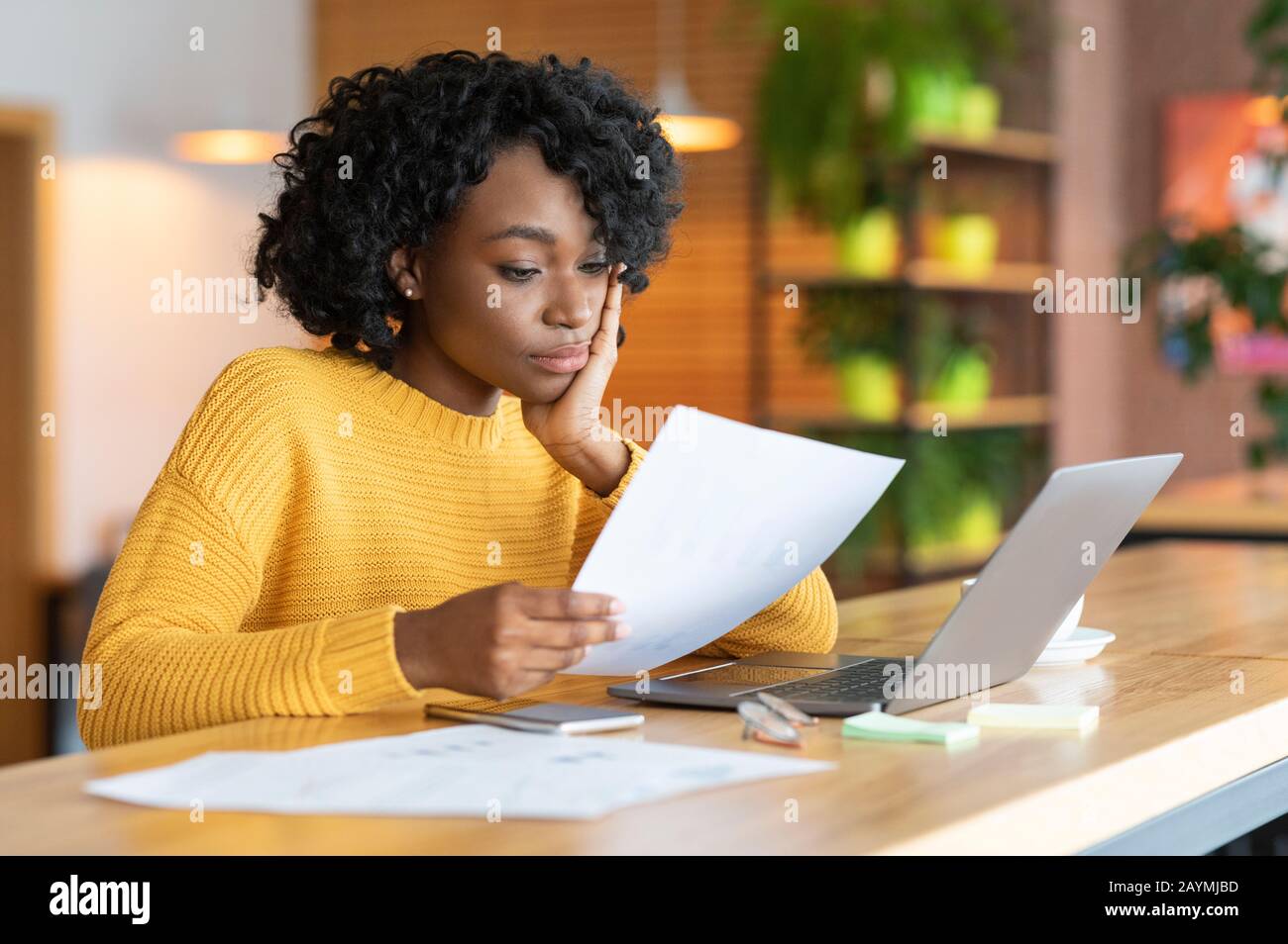 Concentrated afro girl editor working with text at cafe Stock Photo - Alamy