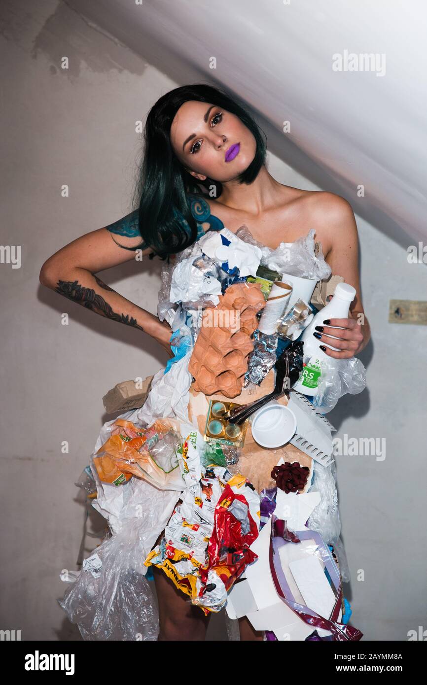 Portrait of smiling female eco fighter wearing trash dress made of ...