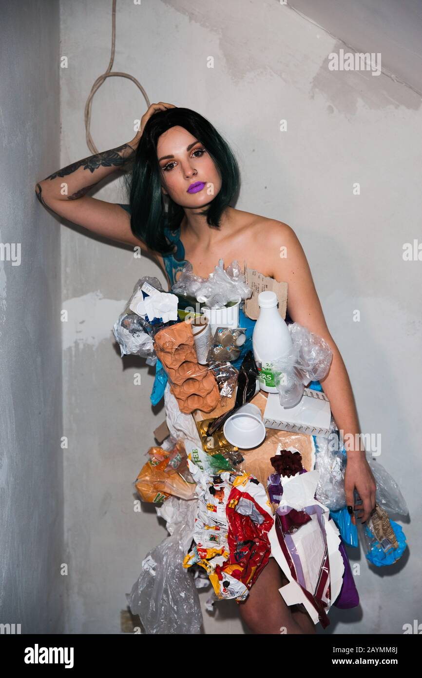 Portrait of smiling female eco fighter wearing trash dress made of ...