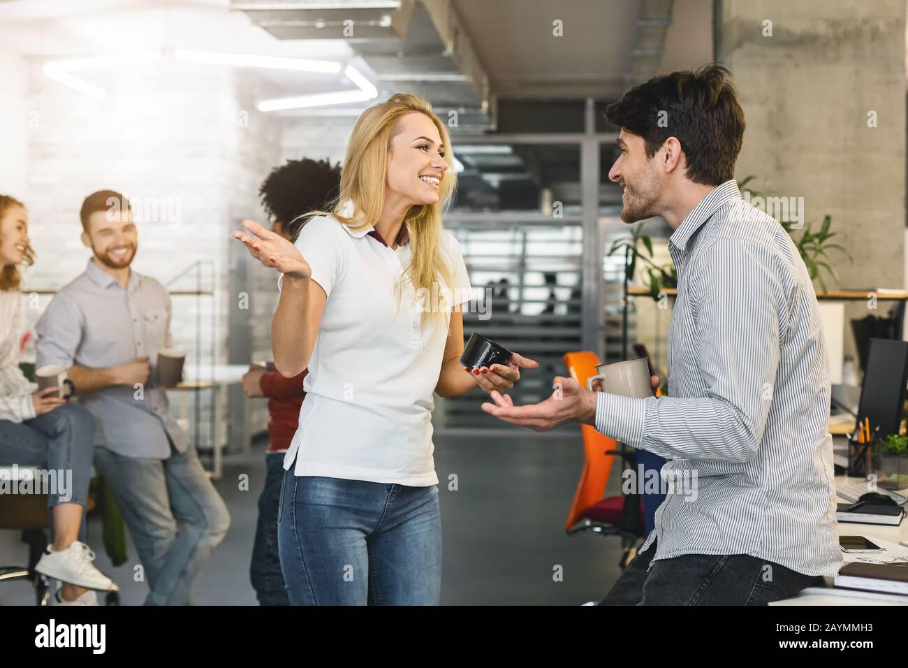Young friendly colleagues having conversation at workplace Stock Photo ...