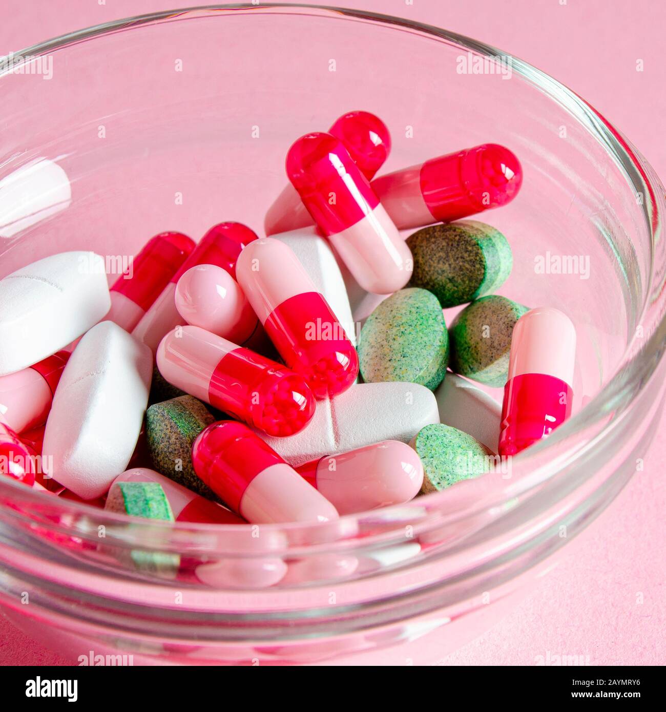 Multi-colored anti-virus tablets of different shapes lie in a glass ...