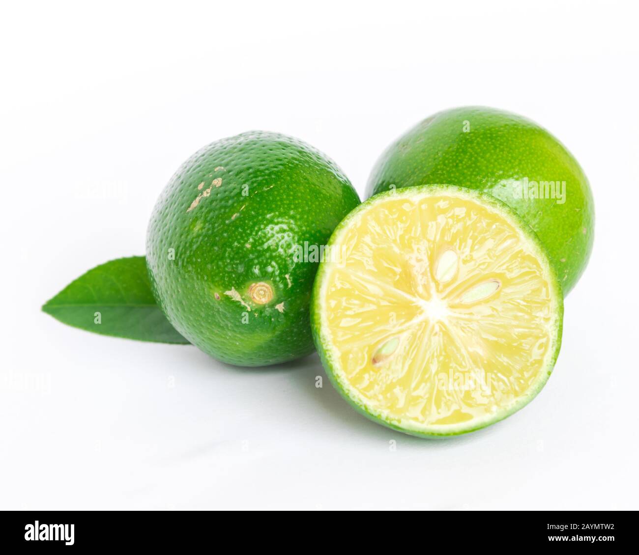 Two homegrown raw Asian limes with half cut slices and green leaves ...