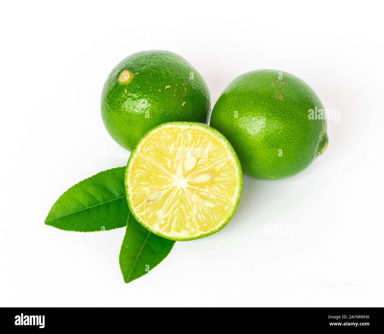 Two homegrown raw Asian limes with half cut slices and green leaves ...