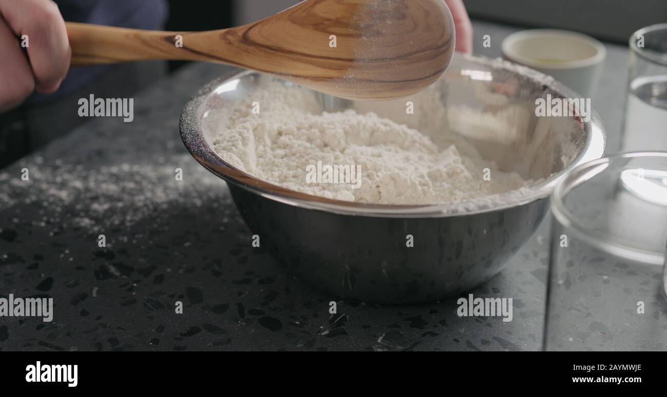 man mixing dry ingredients with flour in steel bowl on concrete ...