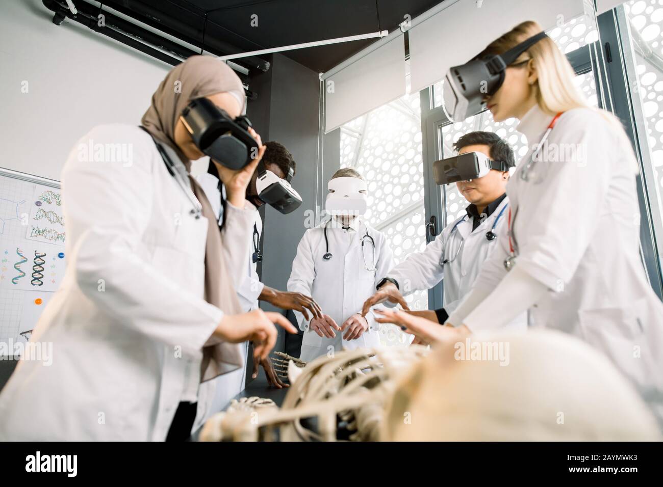 Shot of male professor and four medical students wearing VR goggles and ...
