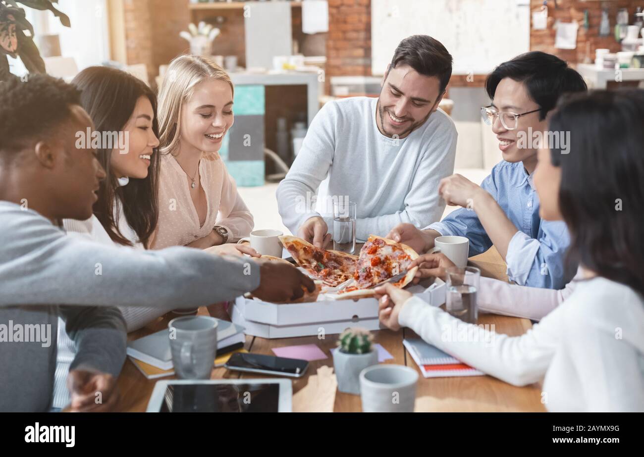 Happy colleagues eating pizza together in office Stock Photo - Alamy