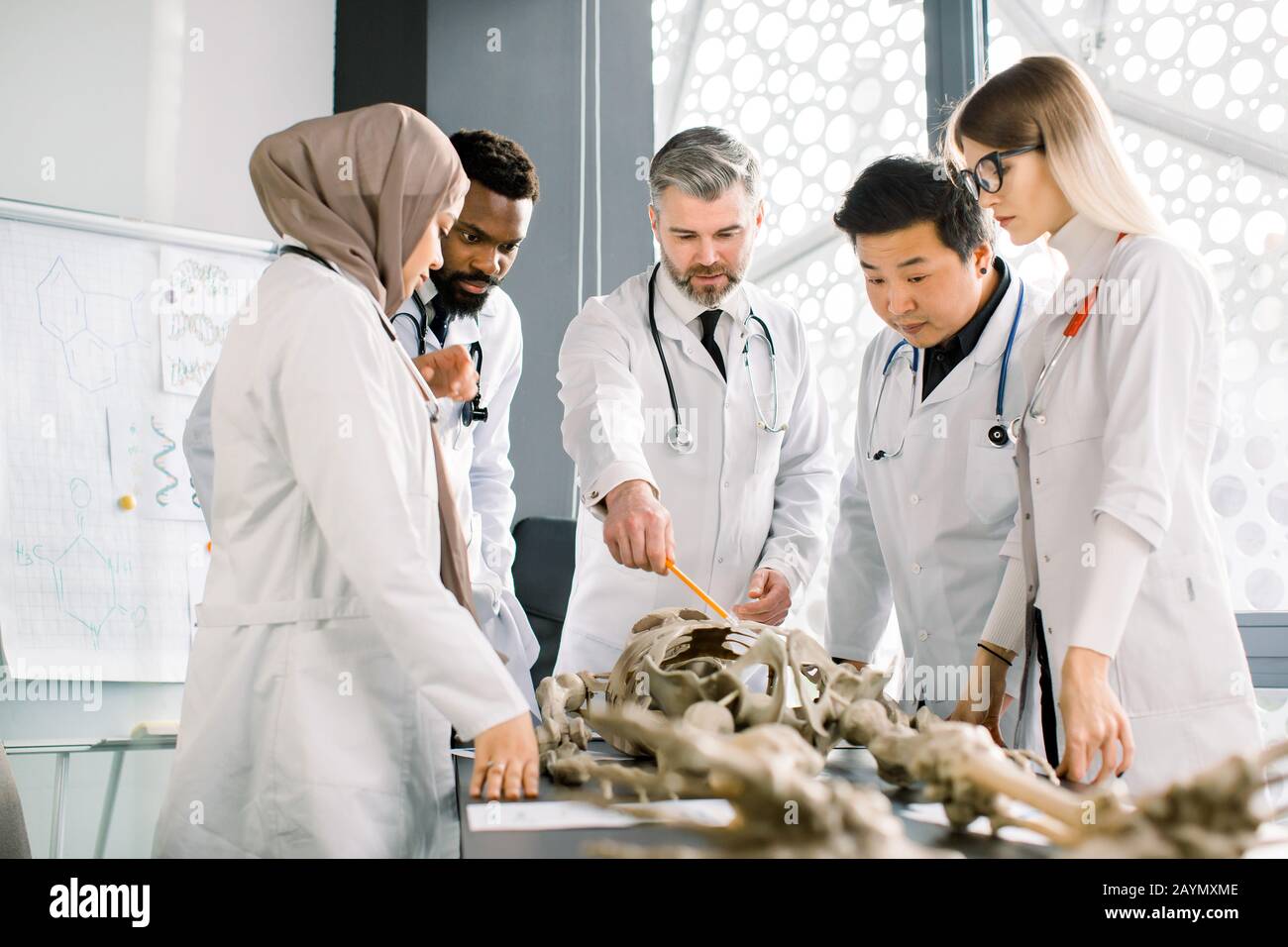 Mature male Caucasian teacher in class, holding a pencil and teaching ...