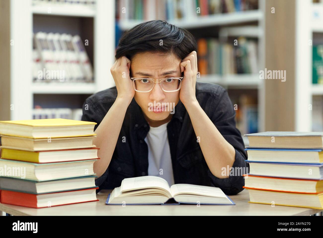 Stressed chinese guy preparing for exam in library Stock Photo - Alamy
