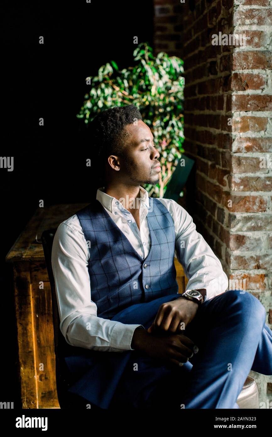 Close up portrait of handsome young male fashion model sitting by a ...