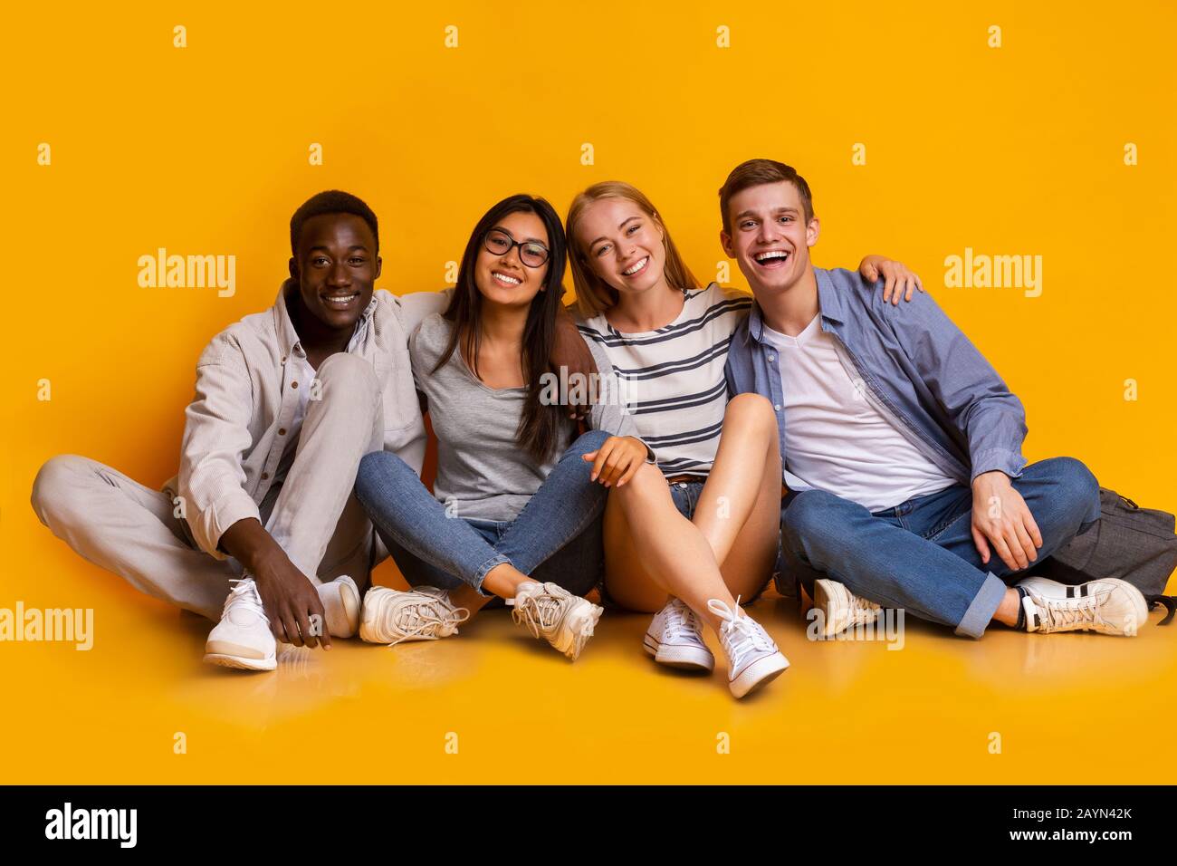 Happy students posing over yellow studio background Stock Photo - Alamy