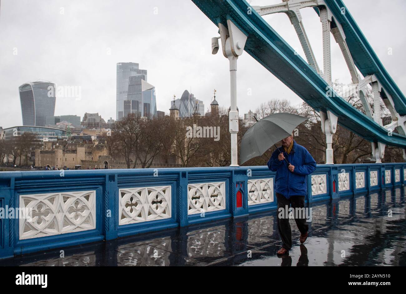 A man crosses Tower Bridge, in London, during a heavy downpour of rain ...