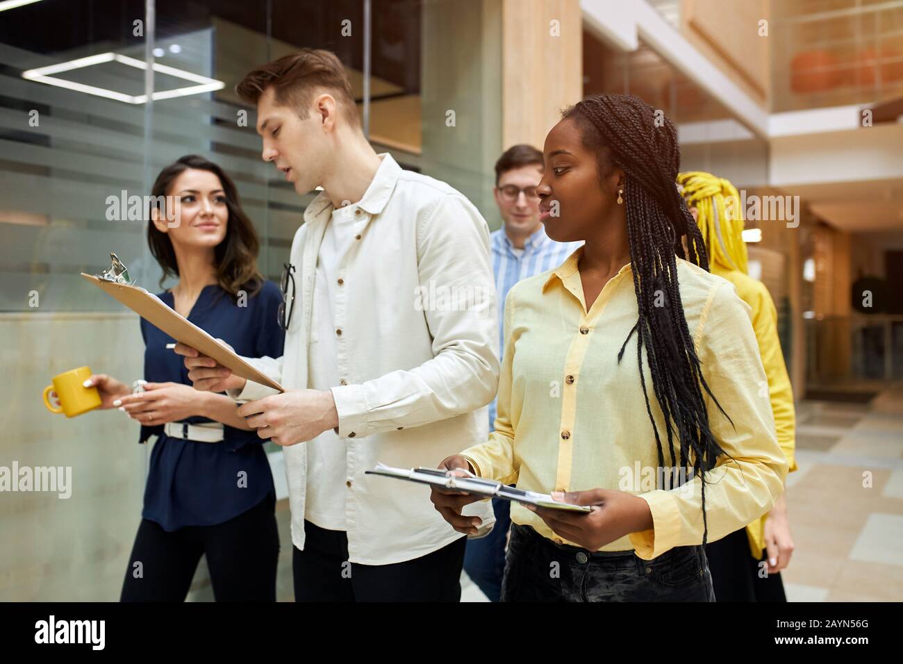 active ambitious people in stylish fashion clothes discussing documents ...