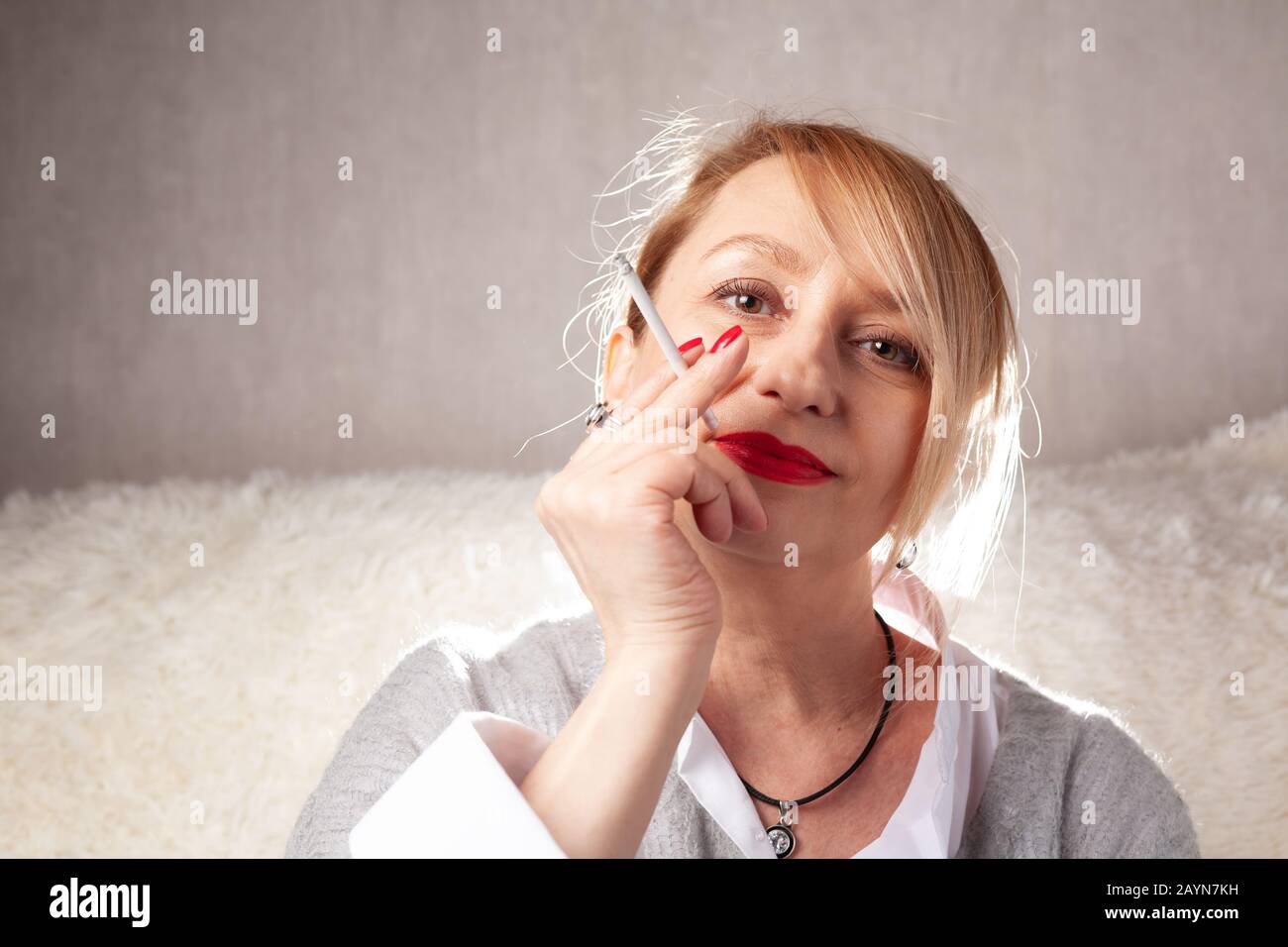 A middle-aged woman smokes in the living room. Stock photo of a happy ...
