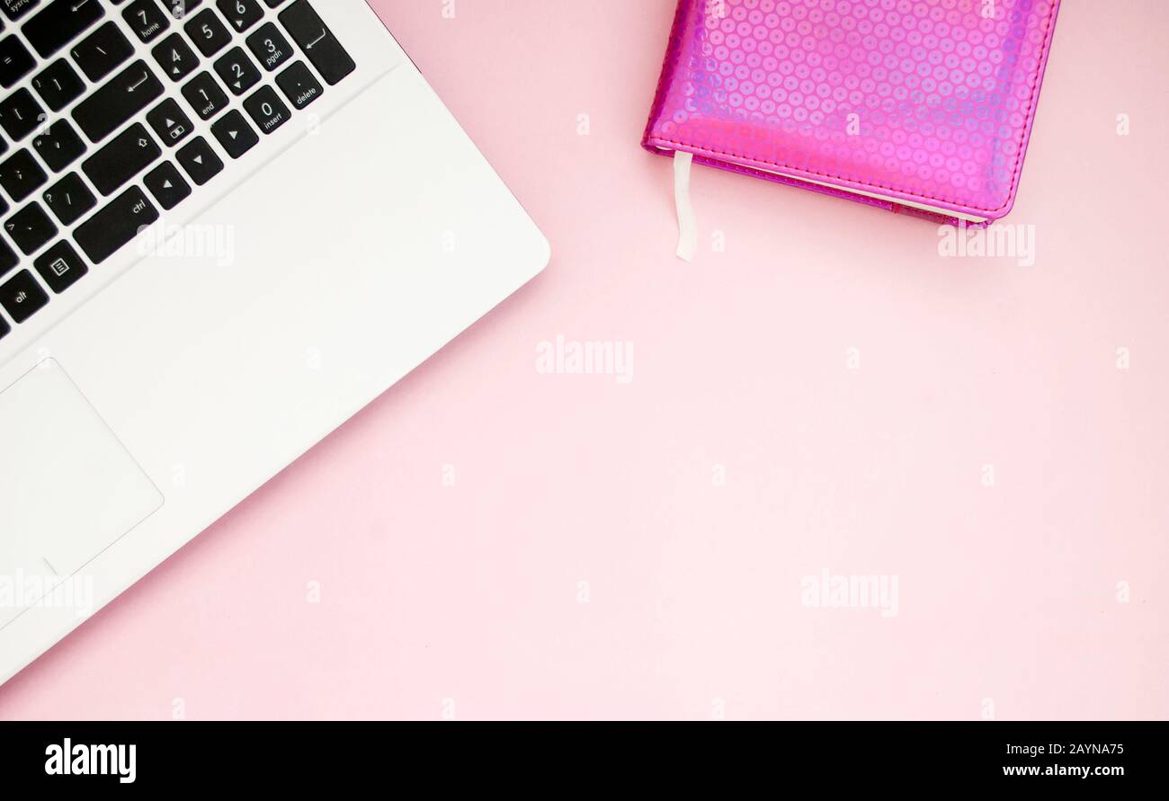 Black-white laptop keyboard, pink notepad, on a pink background. Copy ...