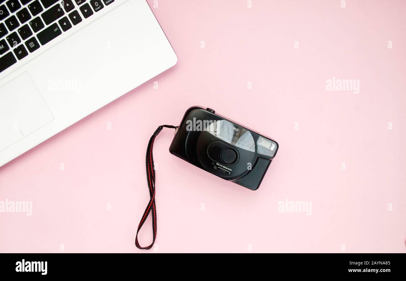 Black and white laptop keyboard, film camera, on a pink background ...