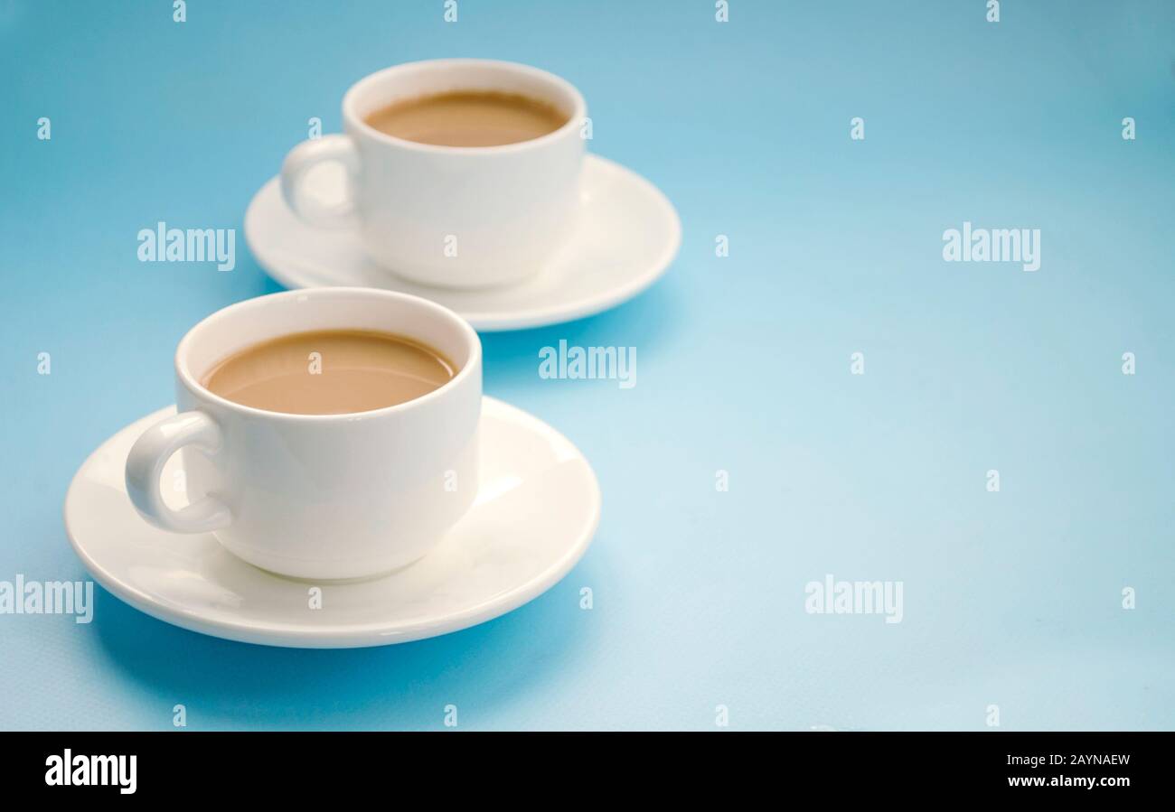Two white cups coffee with milk, light blue background, side view ...