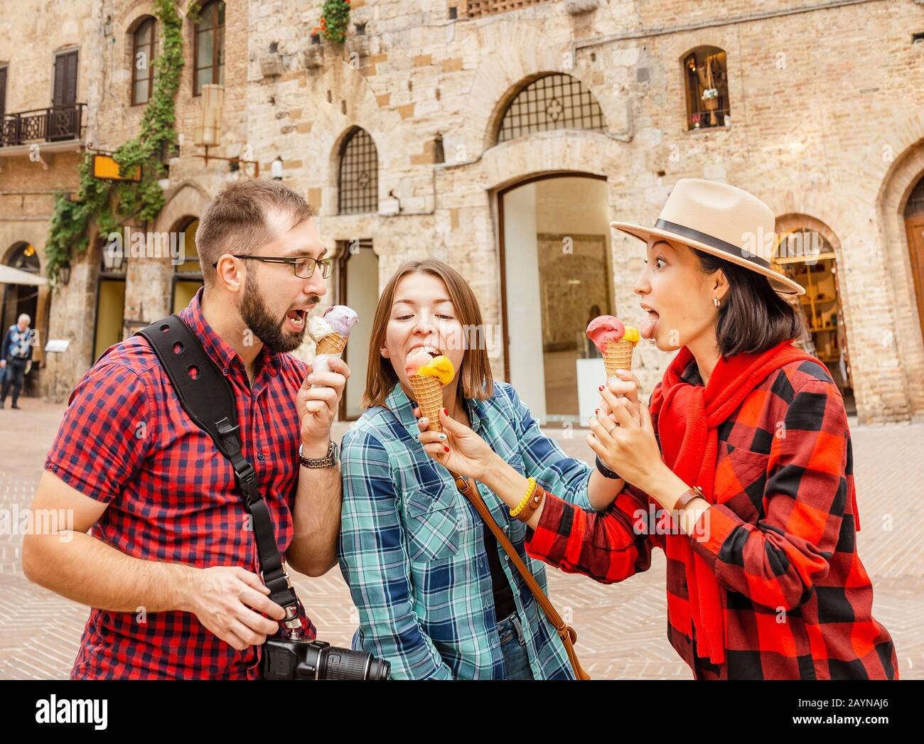 Happy group of friends eating ice-cream in old town center in Italy ...