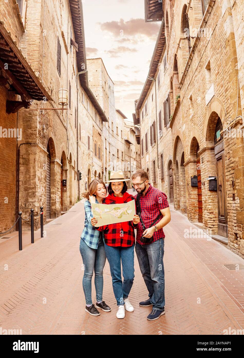 Multiracial group of friends tourists looking at map in an old city in ...