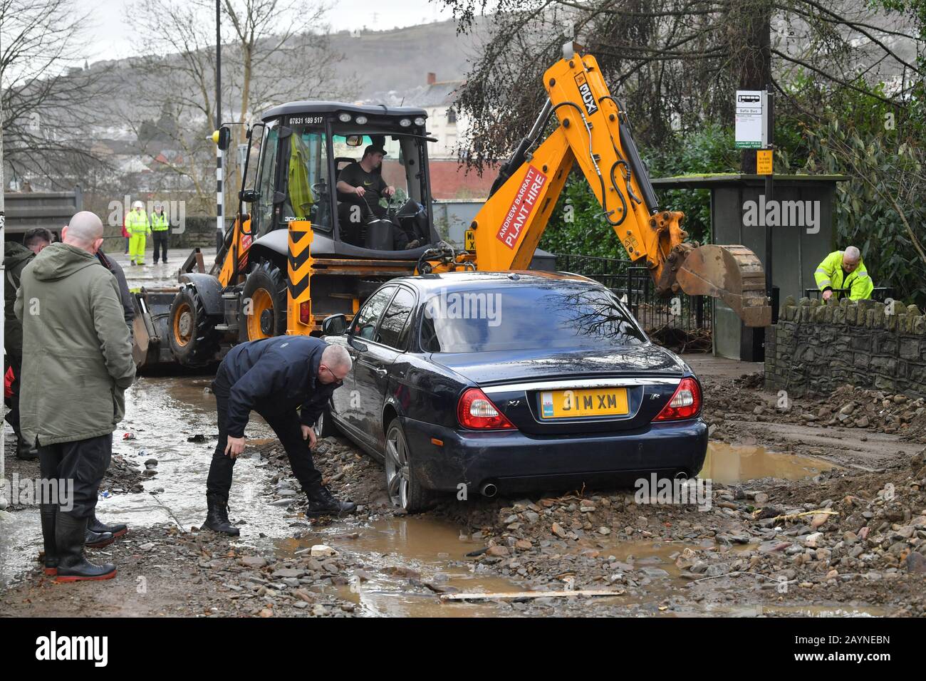 A digger is used to clear debris from a trapped car, carried by ...
